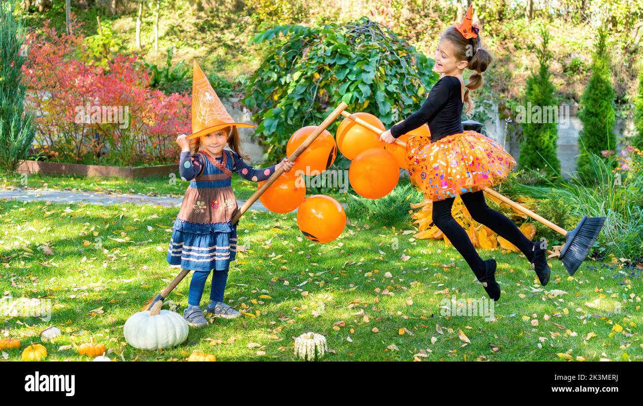 Jump photo of a girl on a broom in a witch costume. Naughty children have fun at the Halloween ...