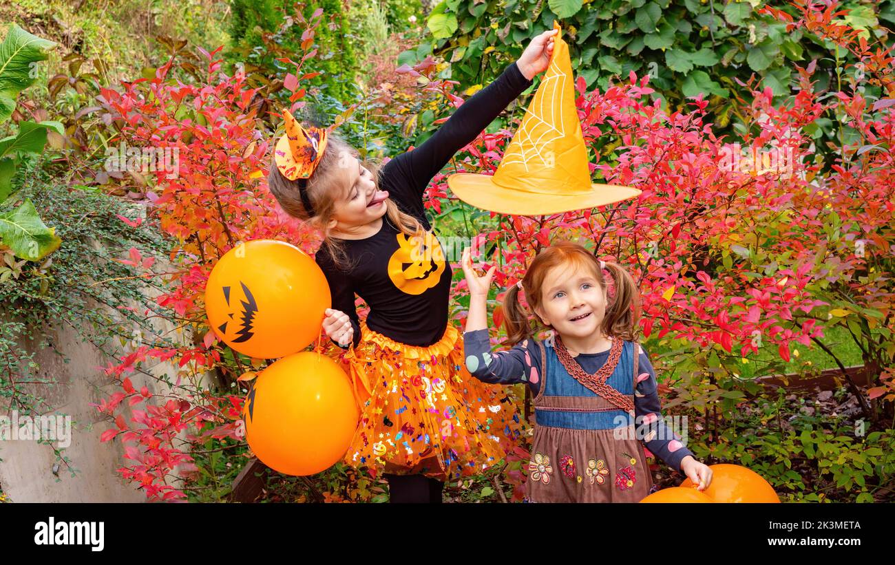 Children in Halloween carnival costumes. Two sisters rejoice and laugh ...