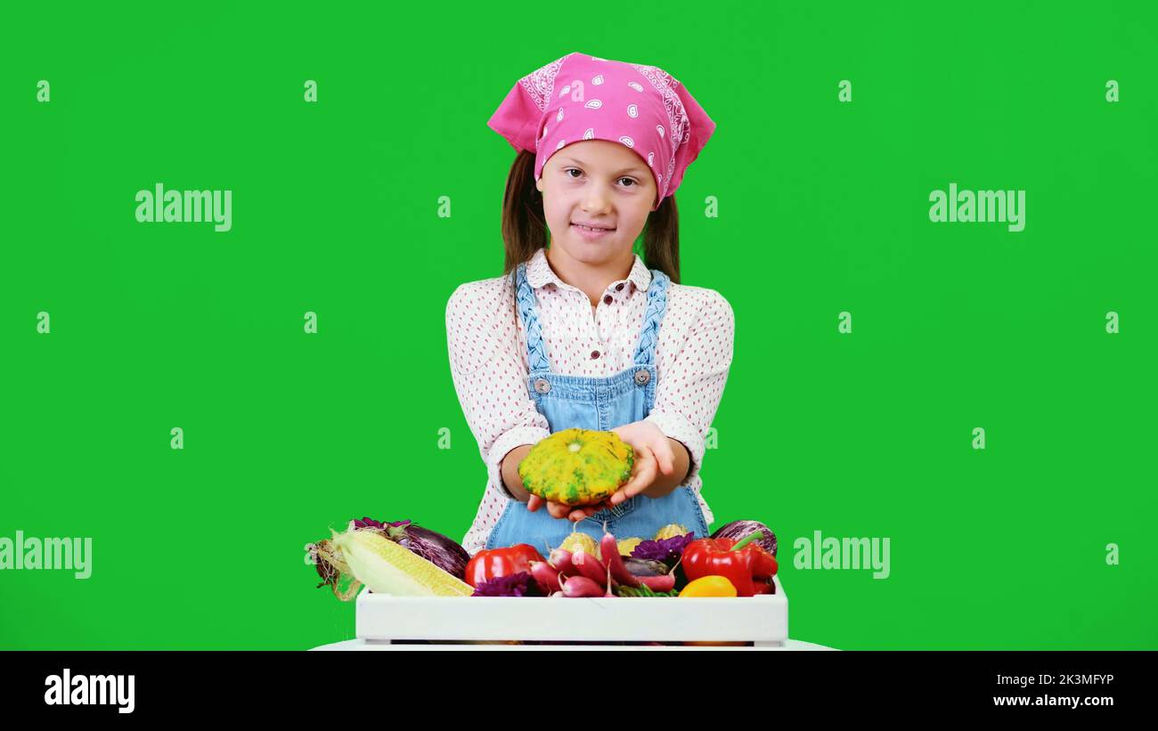 cute, smiling, little farmer girl shows a box with different fresh ...