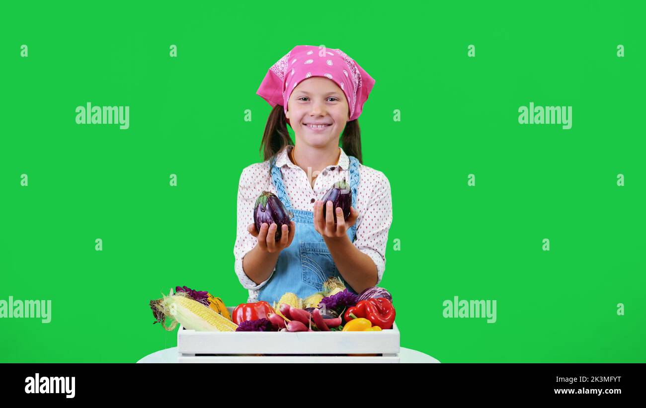 cute, smiling, little farmer girl shows a box with different fresh ...