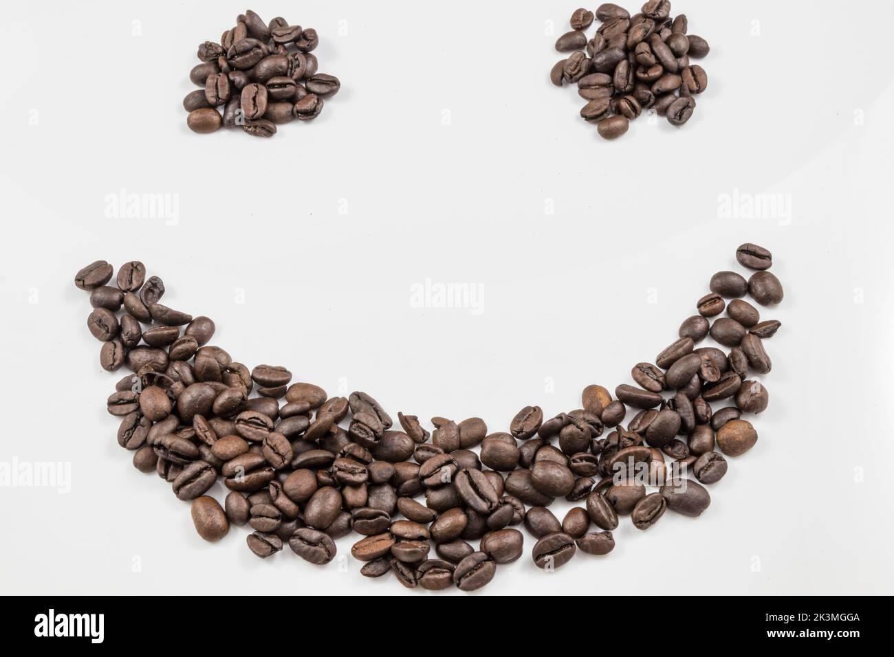 Dark brown roasted coffee beans in the form of smiley face on white ...