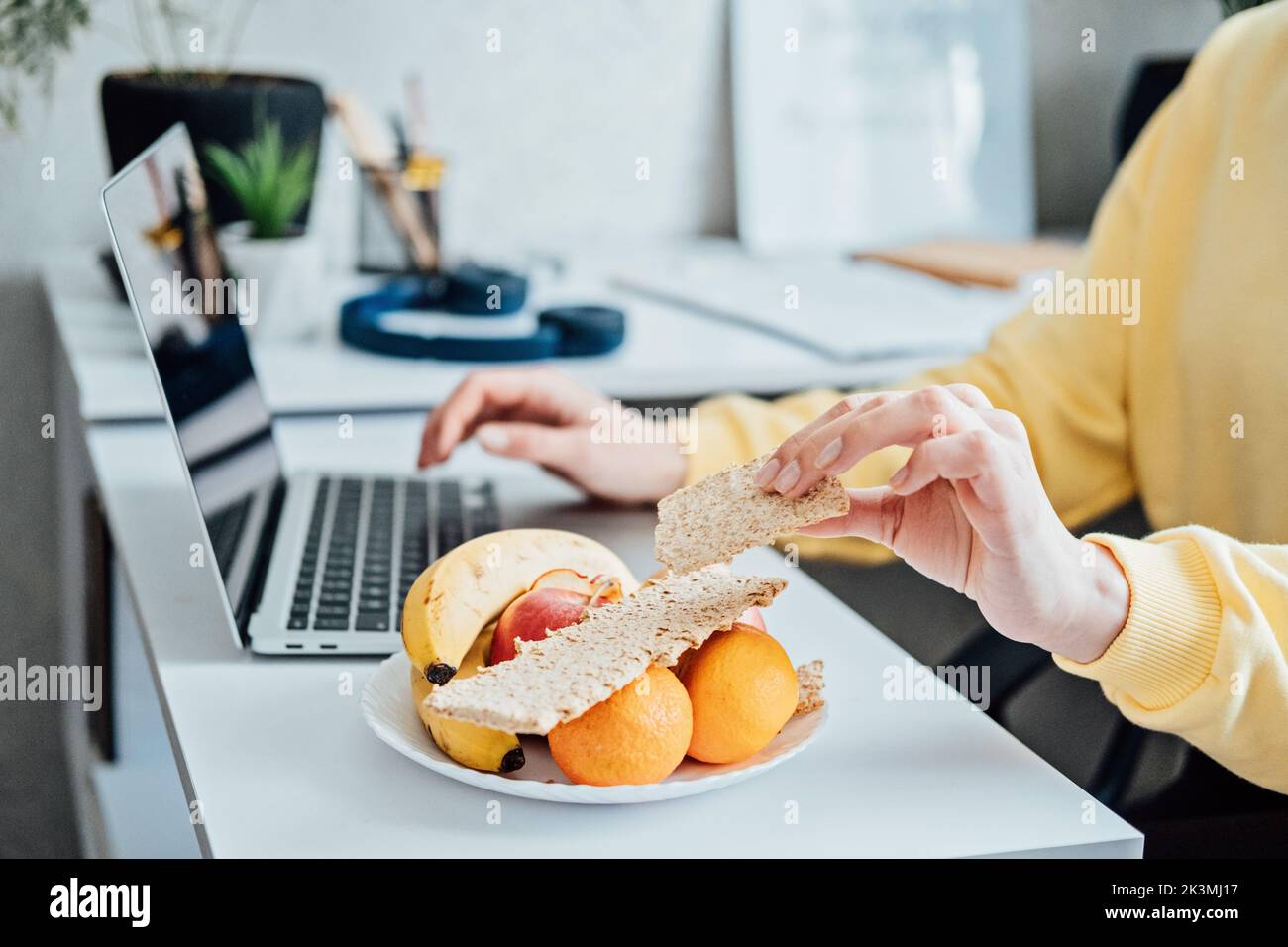 Freelancer young woman eating healthy food when working from home ...
