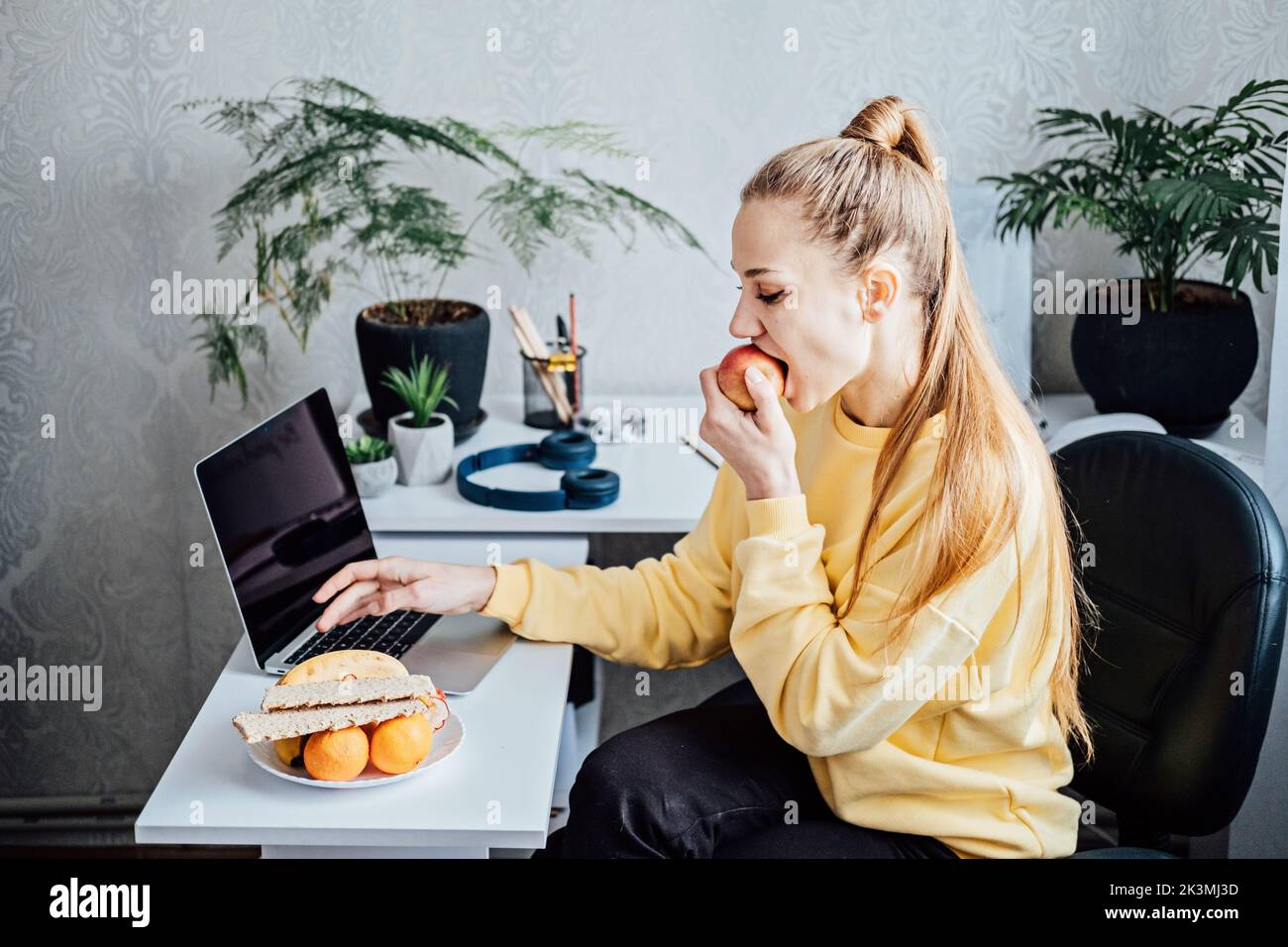 Freelancer young woman eating healthy food when working from home ...
