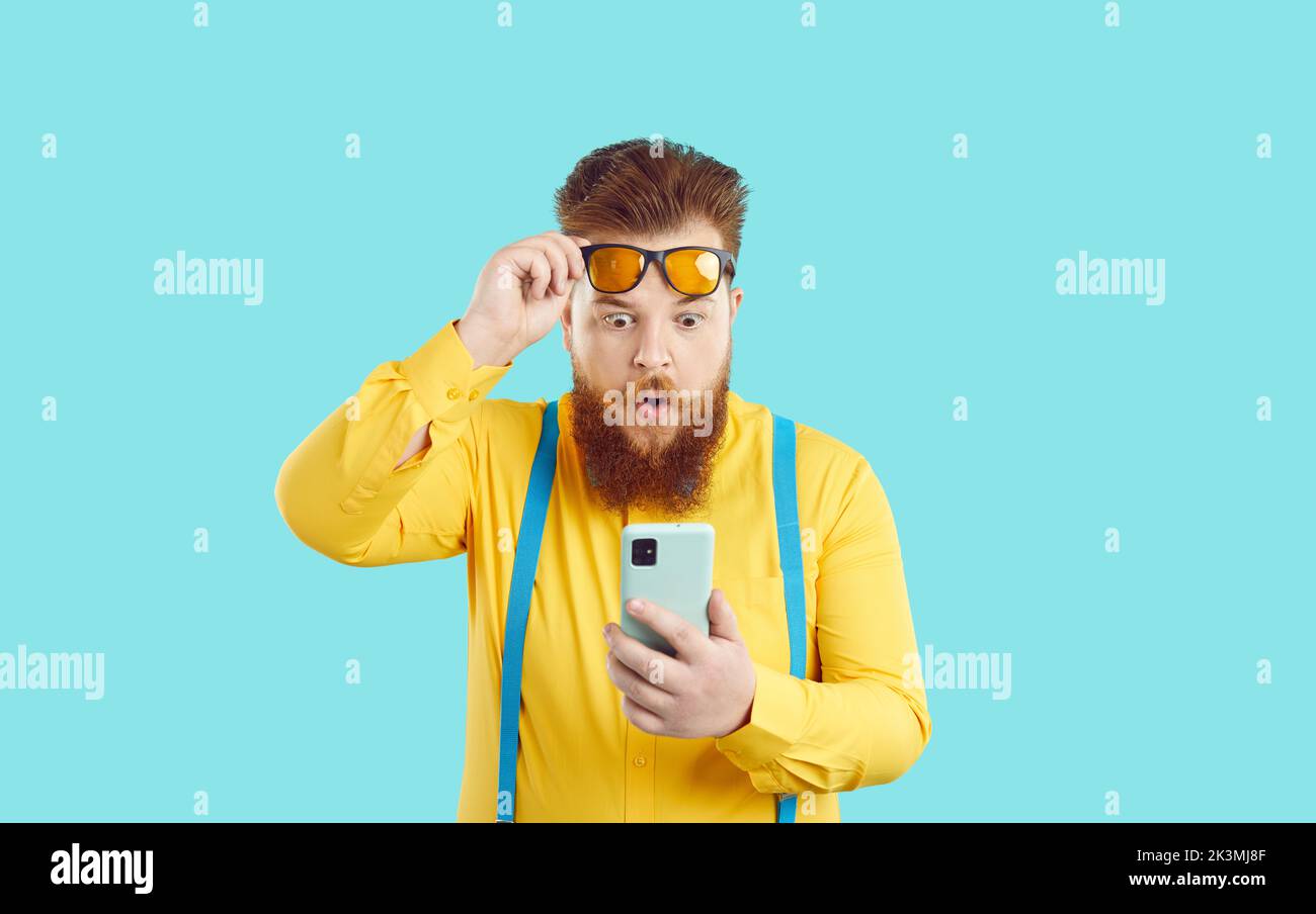 Amazed charismatic chubby man looks in surprise at screen of mobile ...