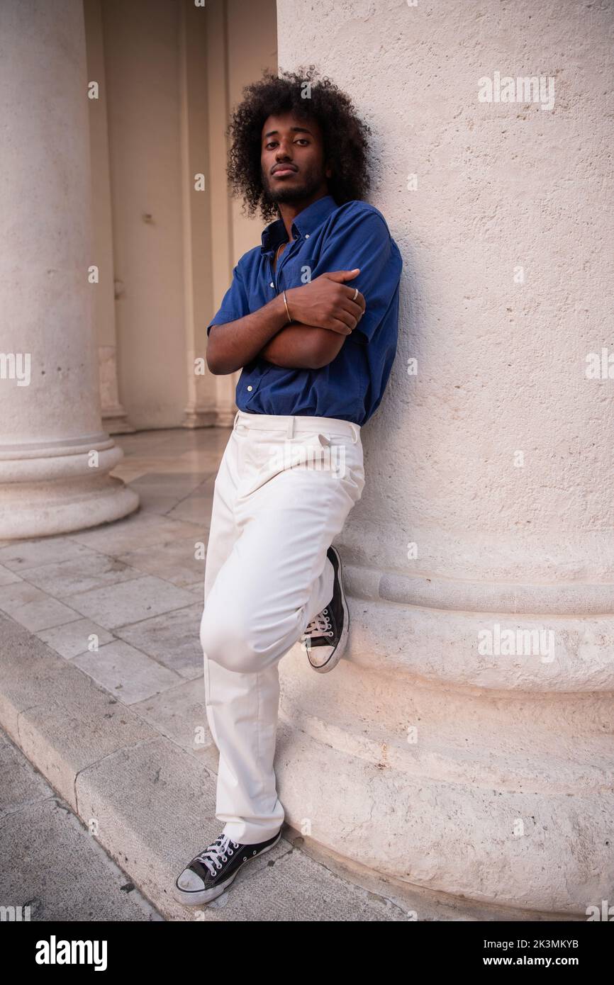 Young black boy leaning against a column in downtown looks thoughtfully ...