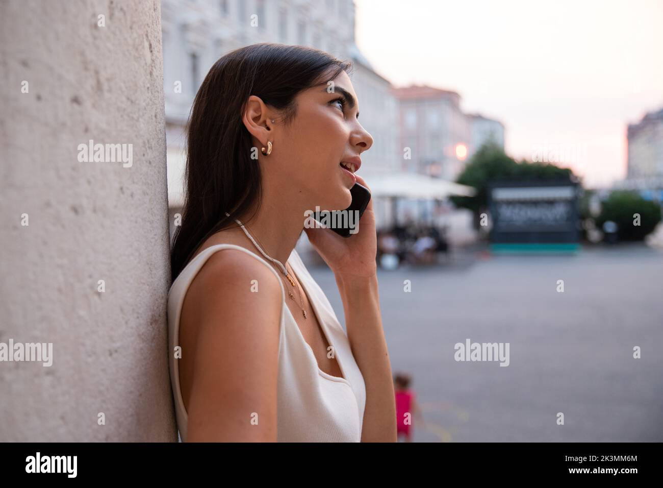 Young brunette leaning against a pole in center city makes a phone call ...