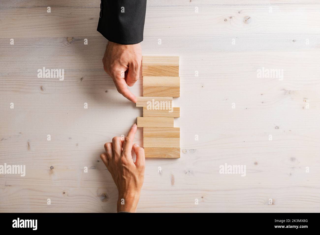 Male and female hands pushing two blank wooden pegs into a stack of ...