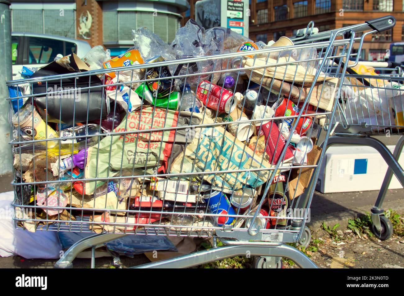 shopping trolley full of rubbish used as a litter bin in a car park ...