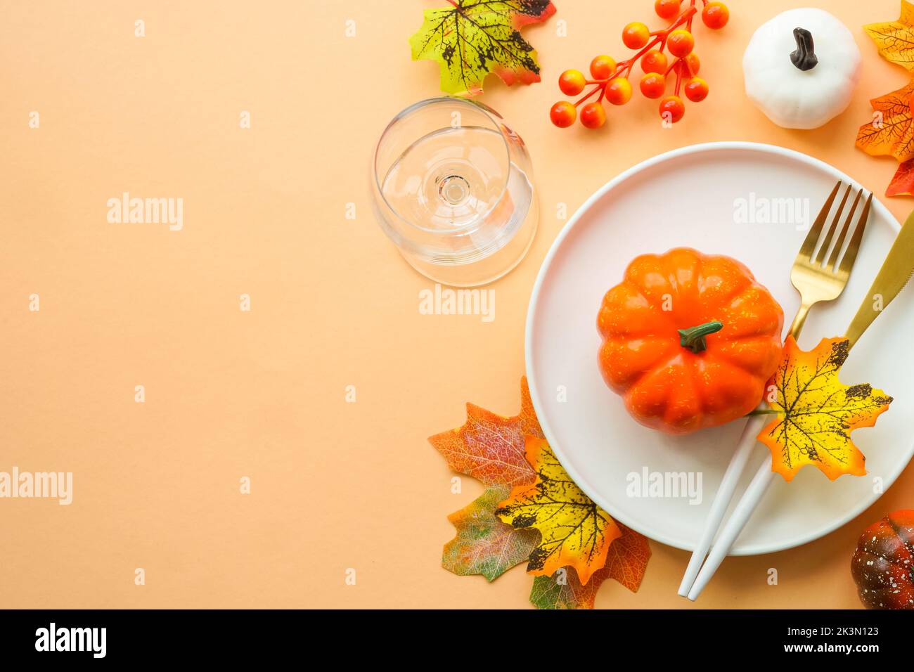Autumn table setting. White plate, golden cutlery and fall decorations ...