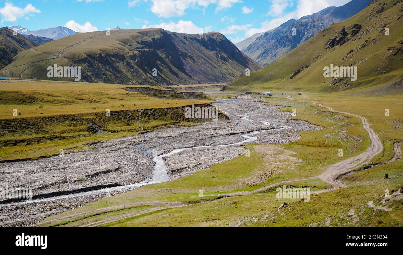 Birds-eye view of a wide valley with narrow torrent river with distant ...