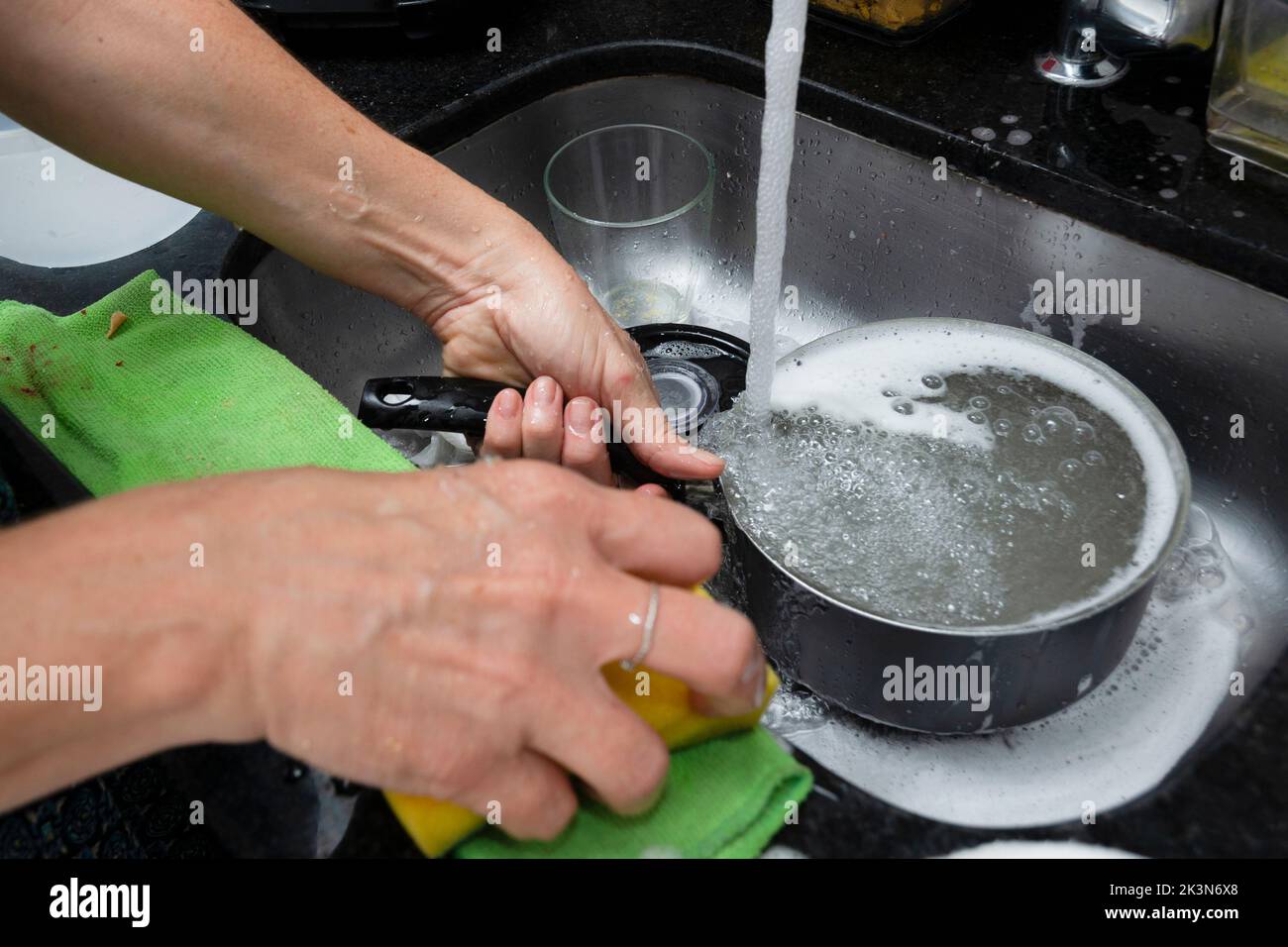 Young woman washing pan and utensils in the kitchen. Hygiene in the ...