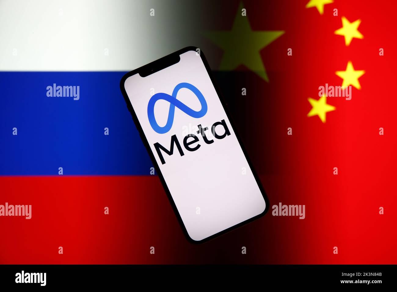 The Meta logo is seen on a mobile phone with Chinese and Russian flags ...