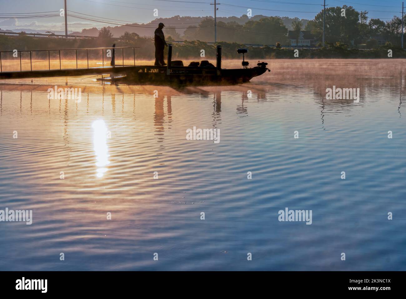 Man going bass fishing in a boat silhouette at a boat dock on Tims Ford ...