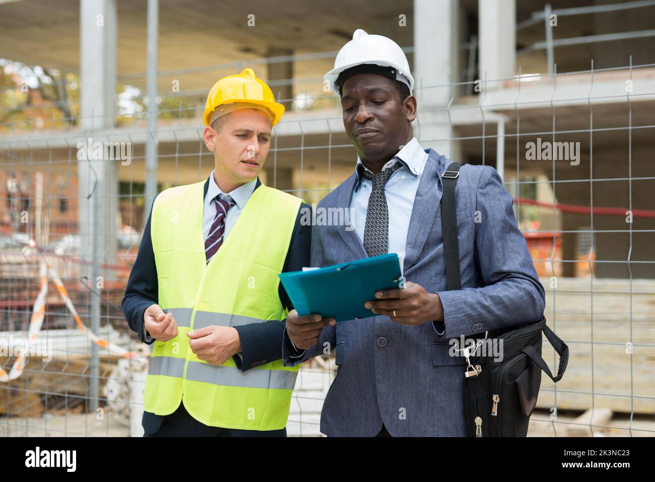 Architect and engineer discussing documentation on construction site ...