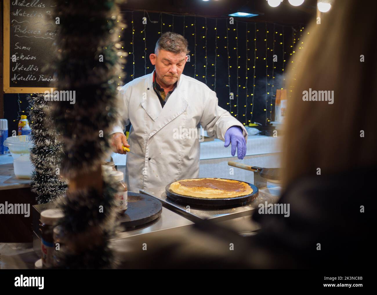 A closeup shot of a man making chocolate pancake in a street stand in ...