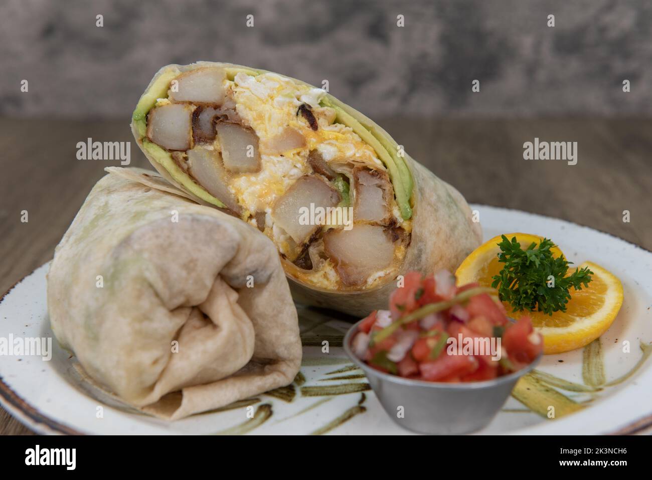 Breakfast burrito cut in half to show the ingredients of scrambled eggs ...