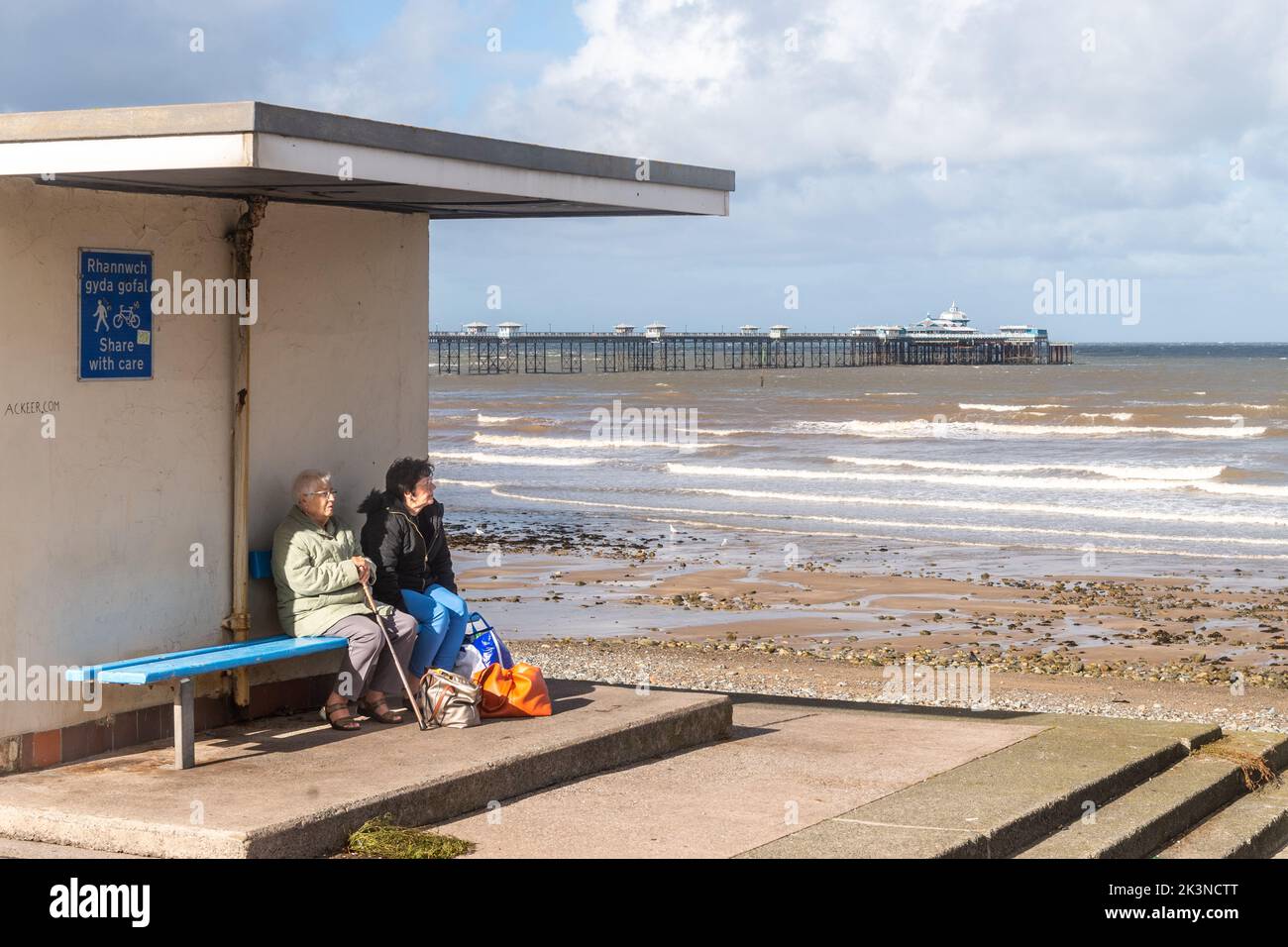 People sitting in a shelter on the promenade in Llandudno, North Wales ...