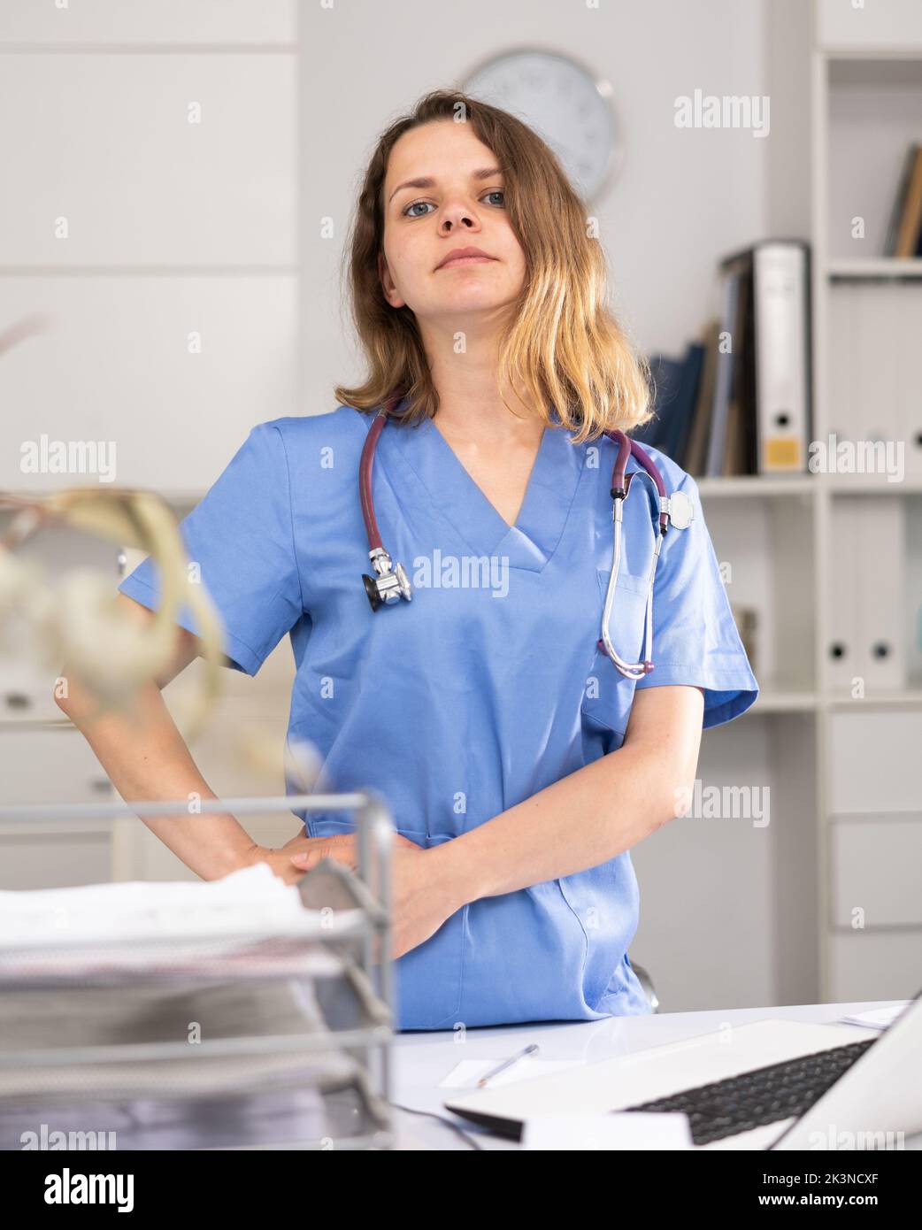 Portrait of female doctor who is working and posing on her workplace in ...