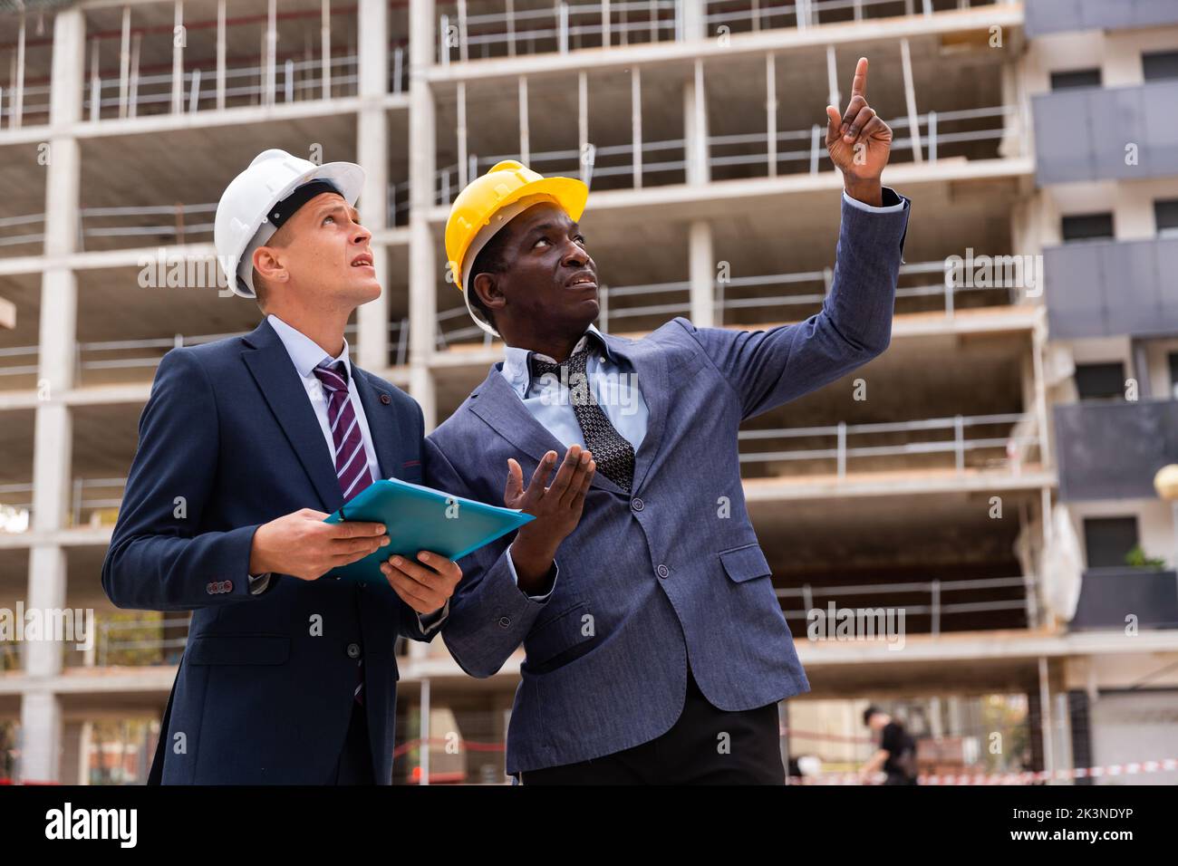 Engineers in suits and hardhats discussing on building site Stock Photo ...