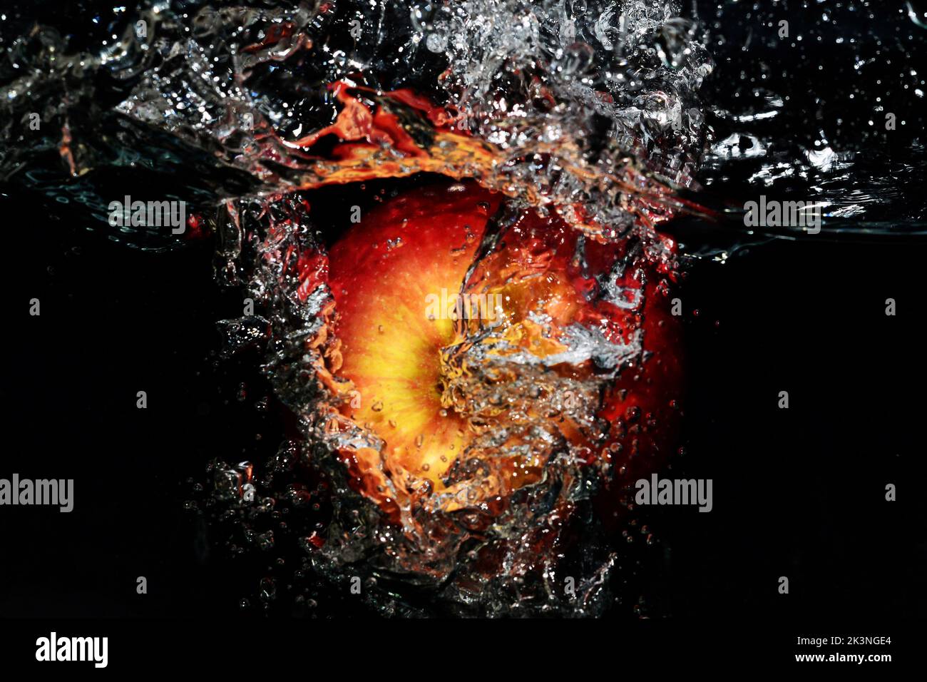 A red apple splash in the water on black background Stock Photo - Alamy