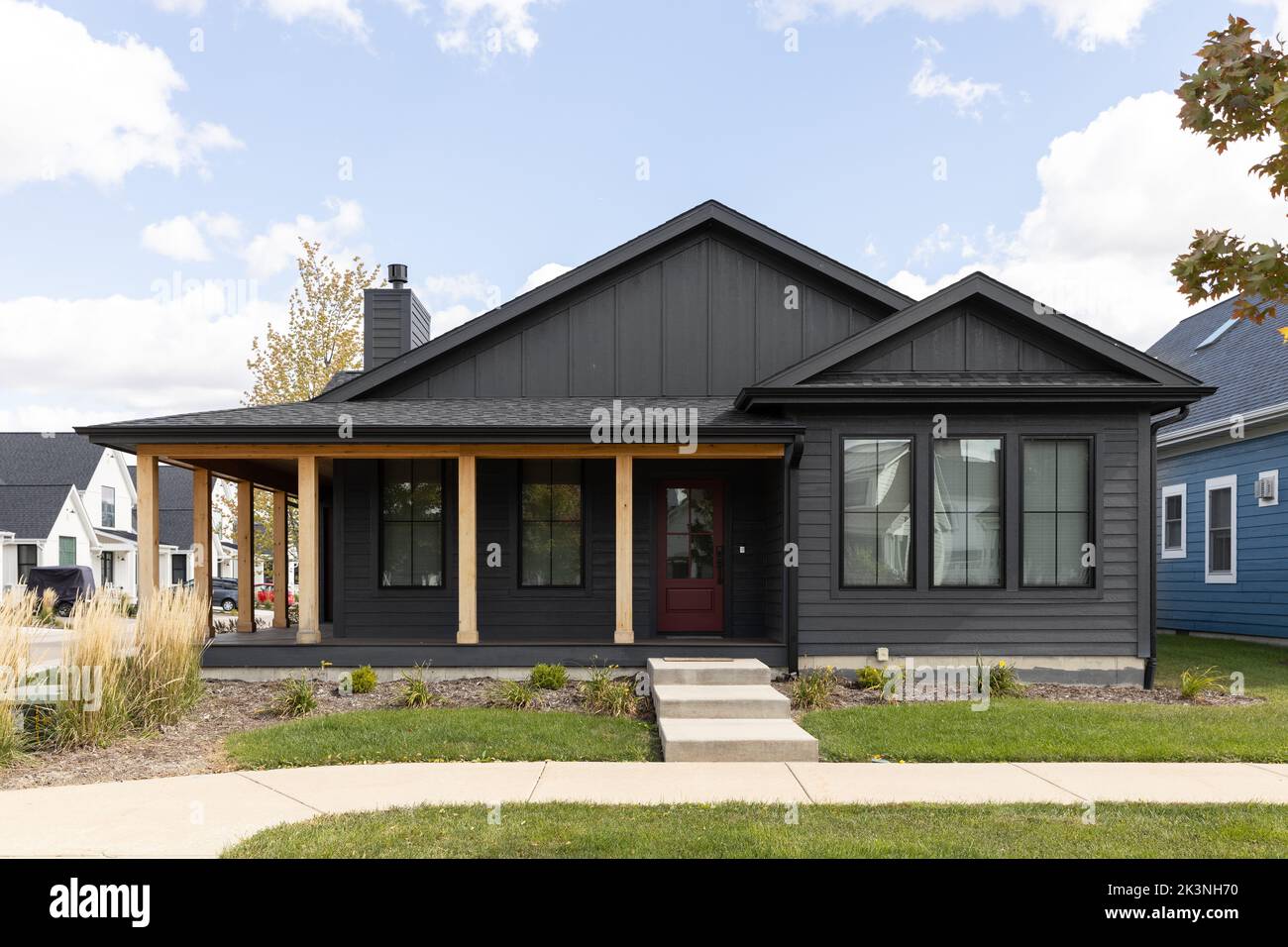 A black ranch home with steps leading to a covered front porch with ...