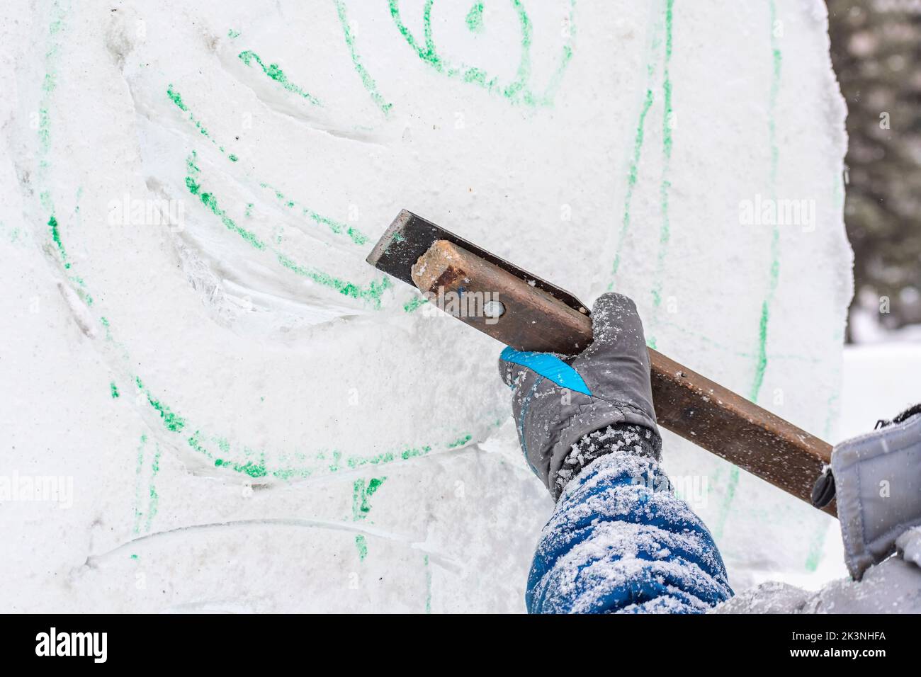 Sculptor artist, using metal knife-cutter, cuts out New Year's ice ...