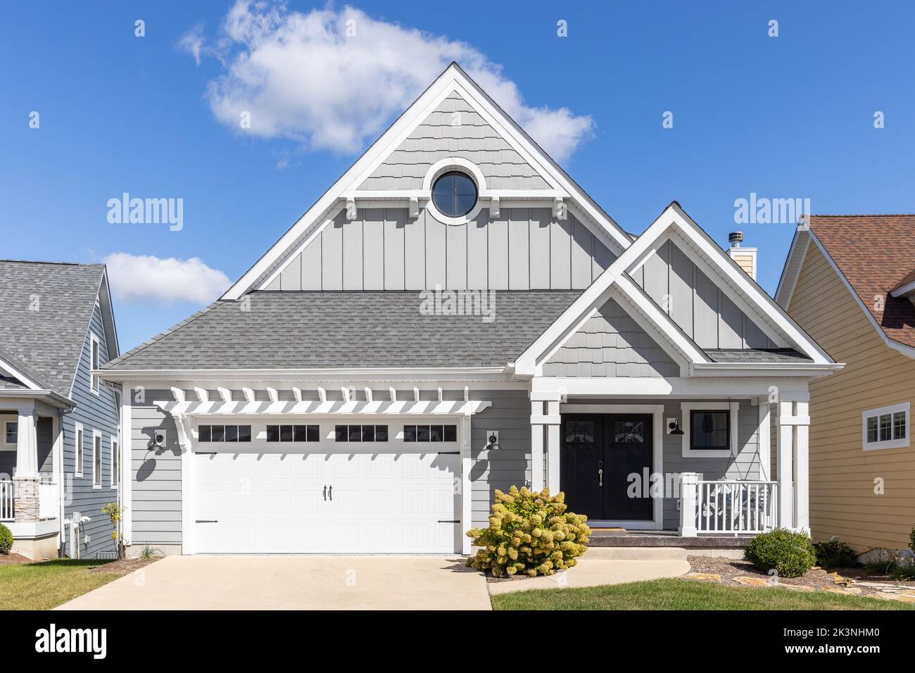 A large grey home with vertical and vinyl siding, pergola style awning ...
