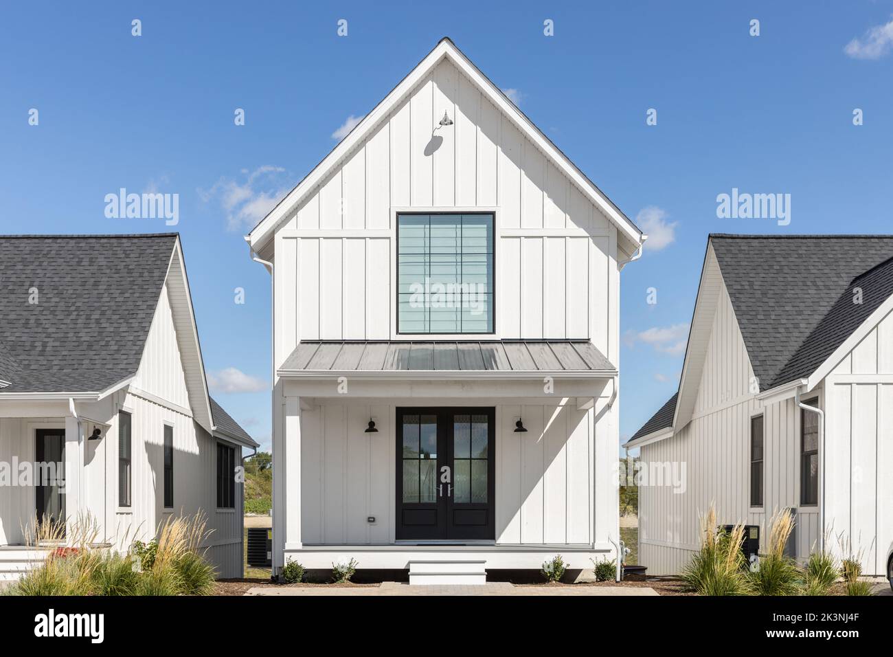 A tall modern farmhouse with white vertical siding, covered front porch ...