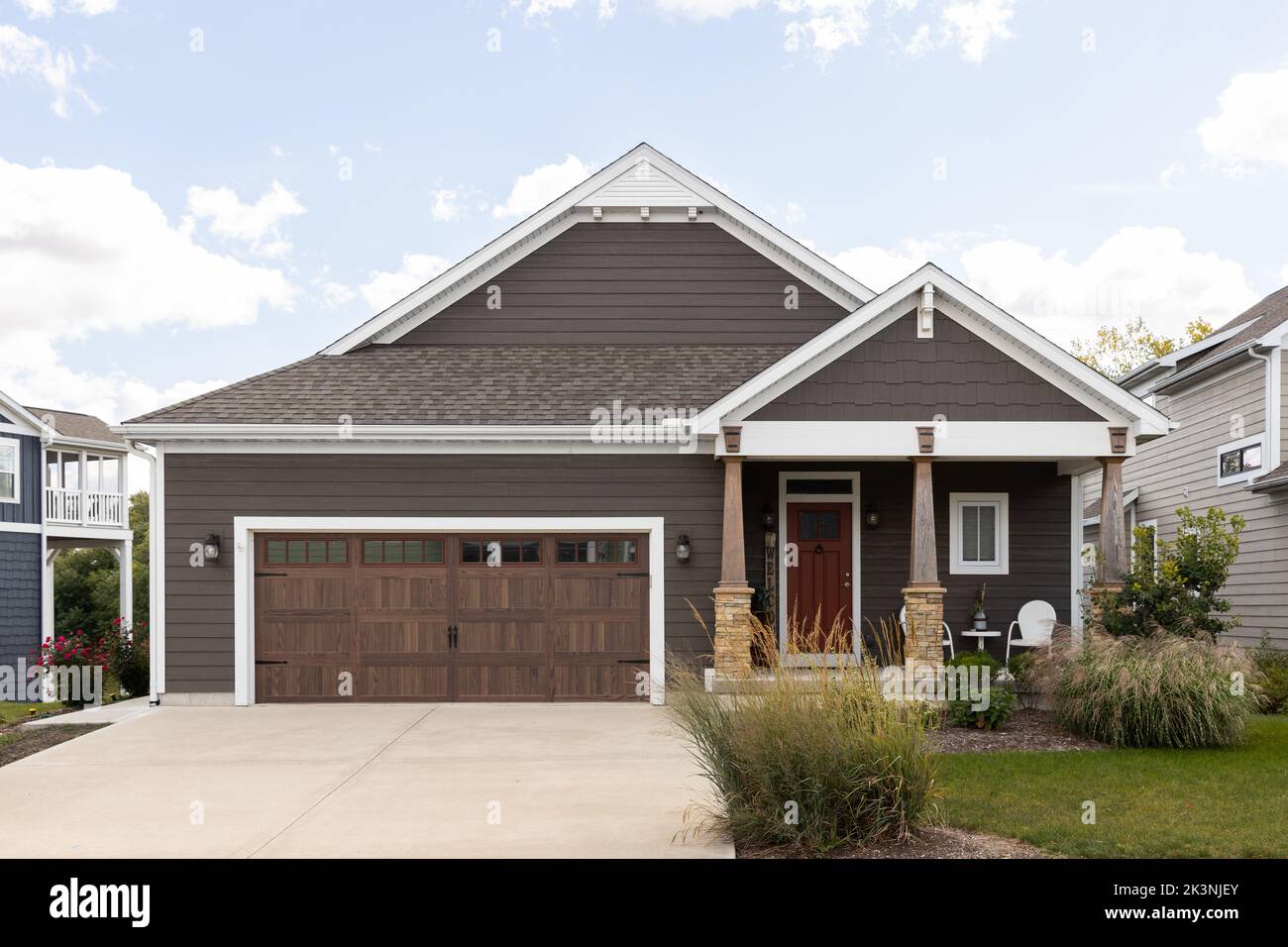 A brown ranch home with a brown garage, covered front porch, and ...