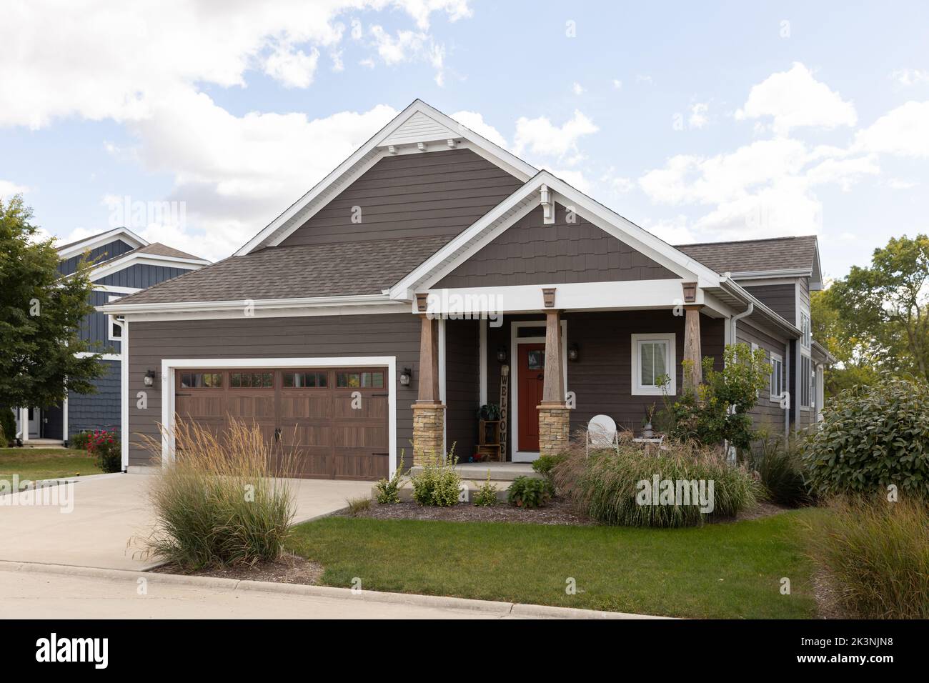 A brown ranch home with a brown garage, covered front porch, and ...
