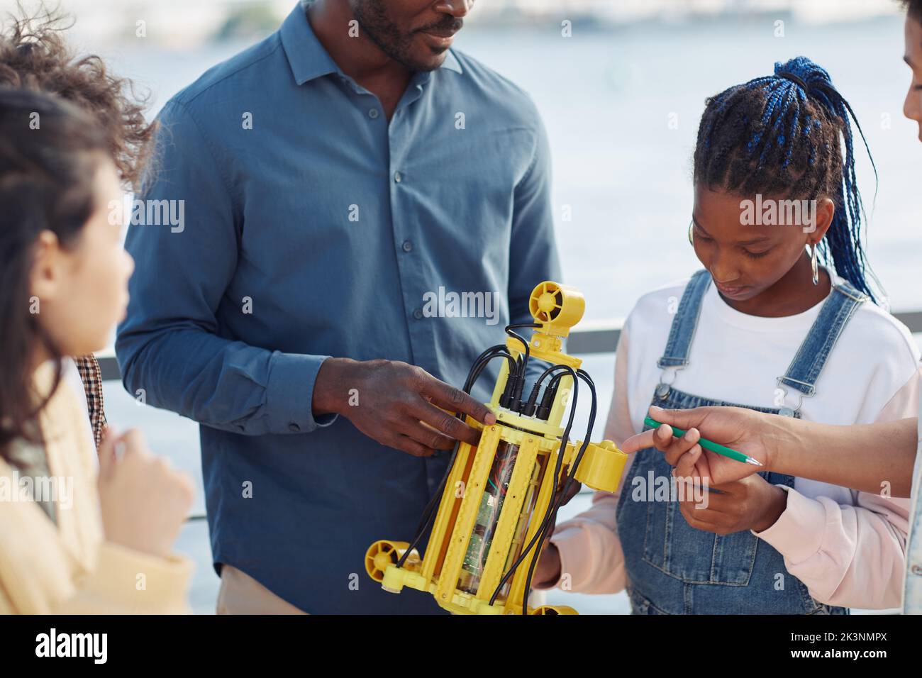 Cropped shot of black male teacher demonstrating robot model to group ...