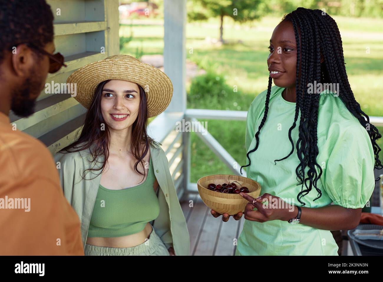 Portrait of three young people chatting at terrace during outdoor party ...