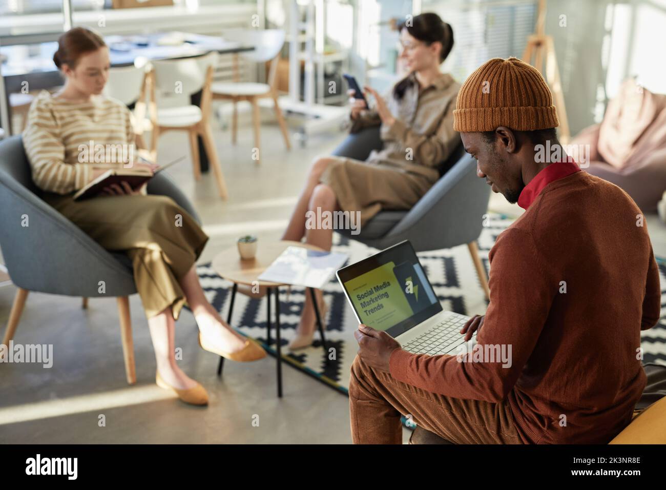 Side view portrait of young black man typing at laptop with marketing ...