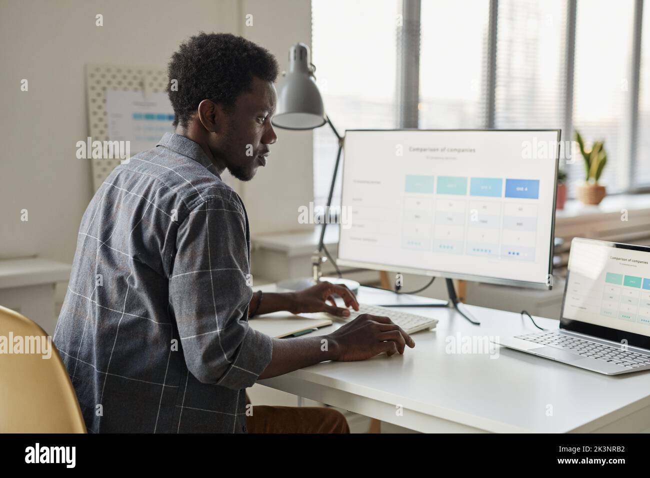 Minimal side view at young black man using computer at workplace in office setting Stock Photo ...