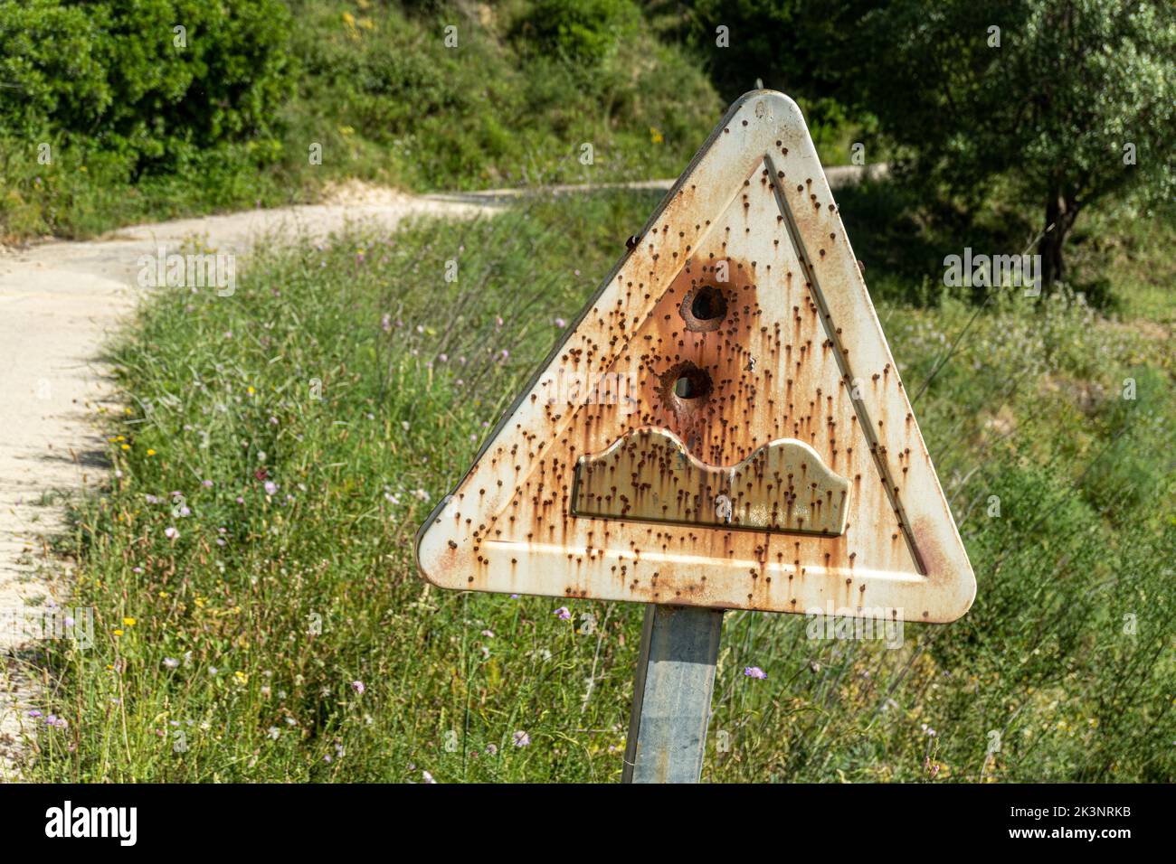 The close-up view of an old dirty warning sign by the countryside road ...