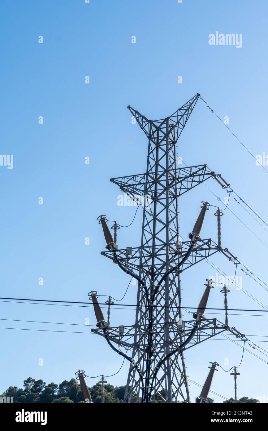 A vertical shot of high voltage electricity tower with blue sky ...