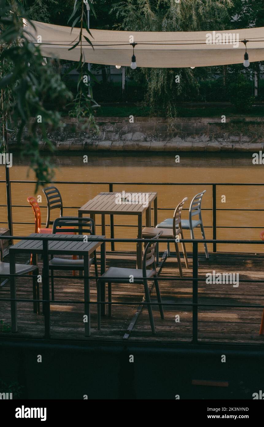 A vertical closeup shot of wooden tables and chairs on the outside of a ...
