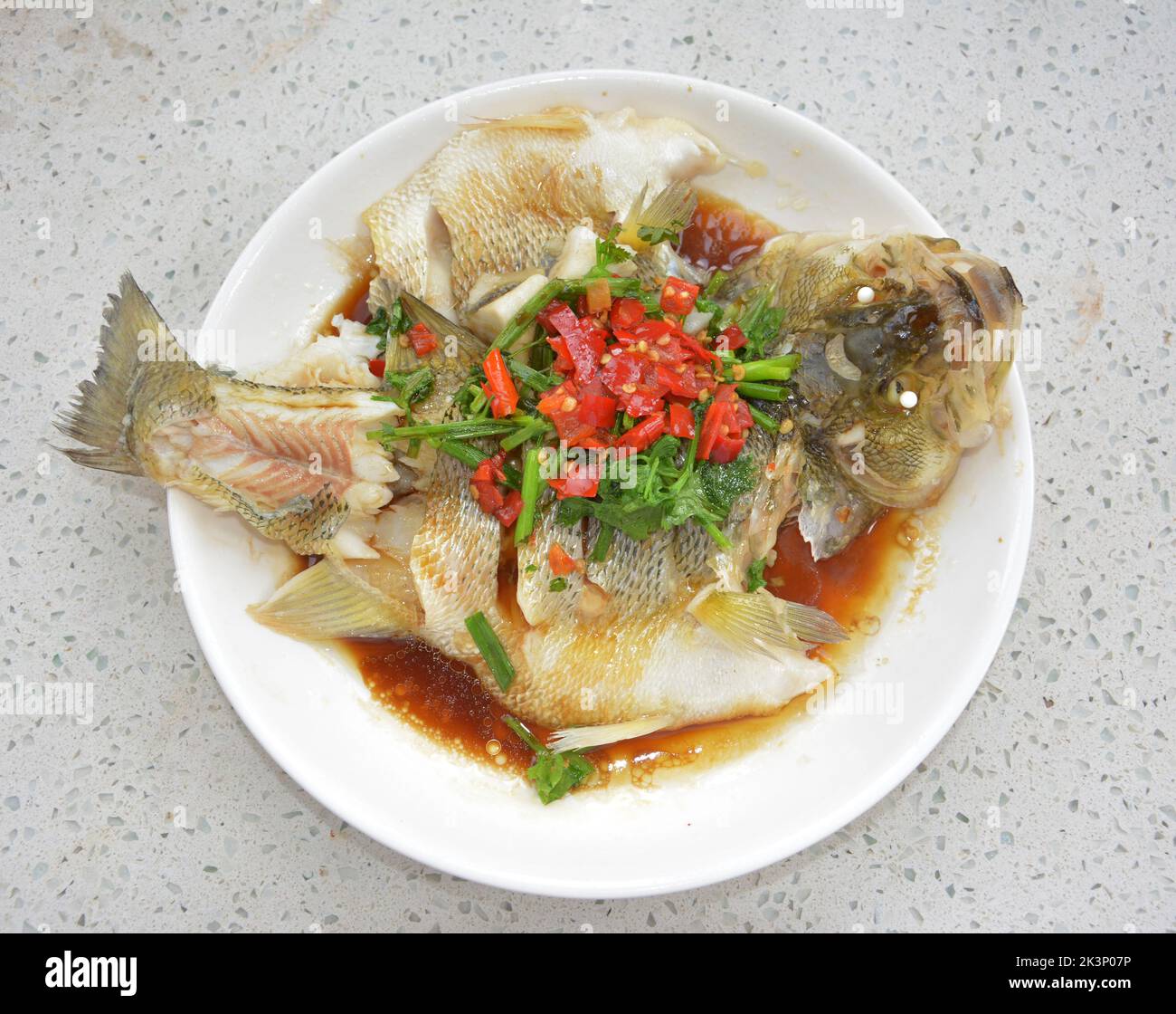 braised fish with green vegetables and red peppers on the plate for ...