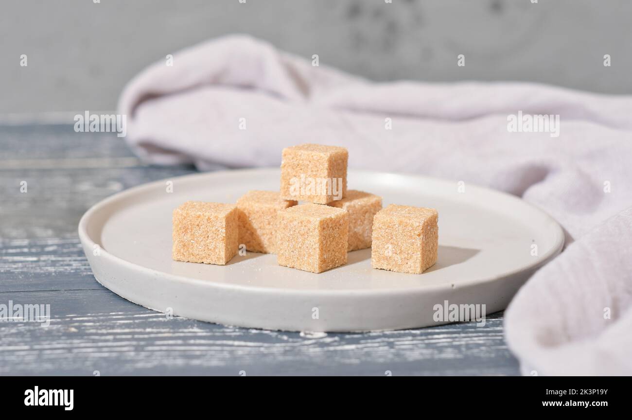unrefined brown cane sugar cubes on cement plate. stack of natural ...