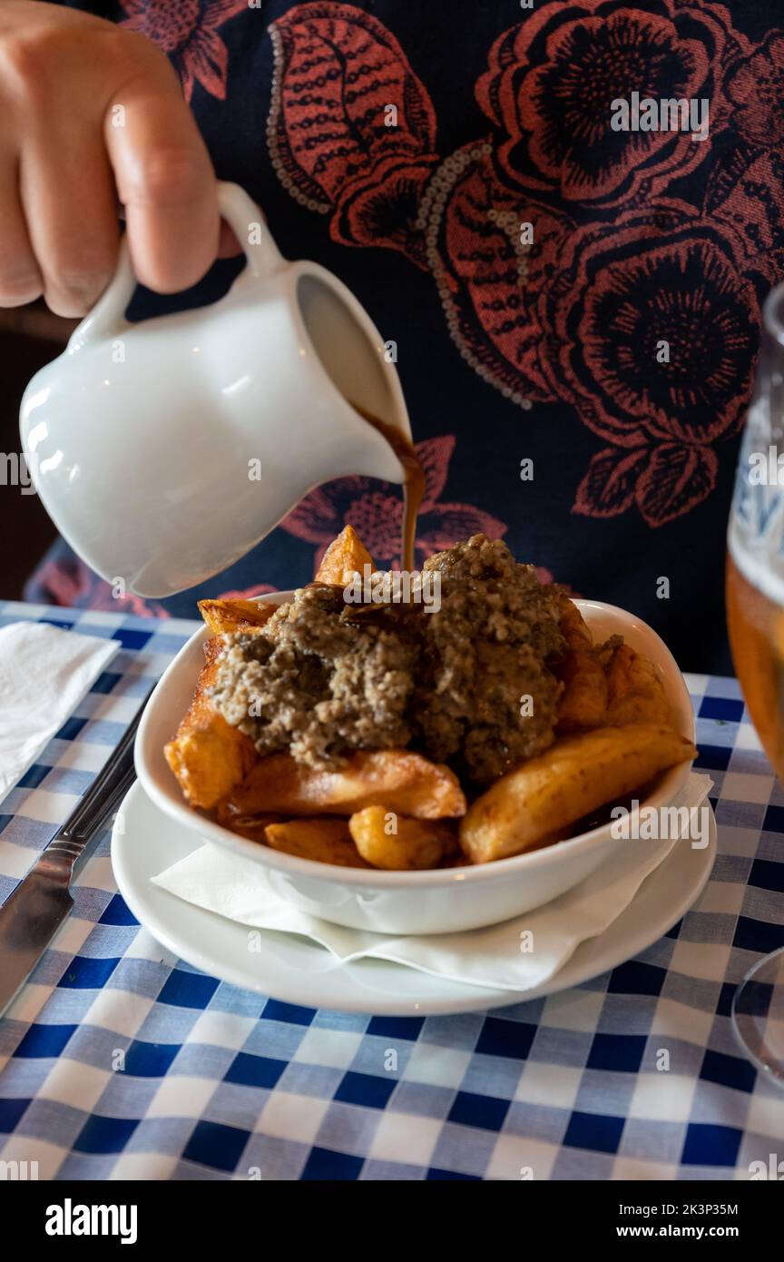 Scottish traditional snack food, hand cut potato chips topped with ...