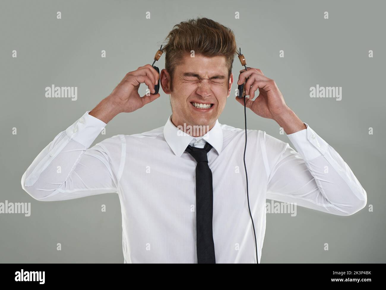 Turn it down. A young man pulling his headphones away from his ears ...