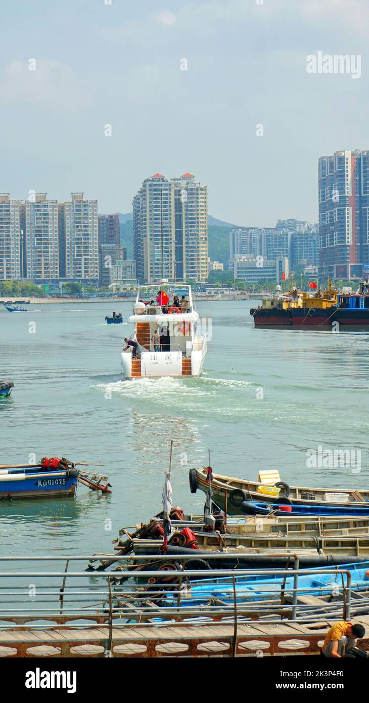 A vertical closeup of a port with ships in the urban area of Shanwei ...