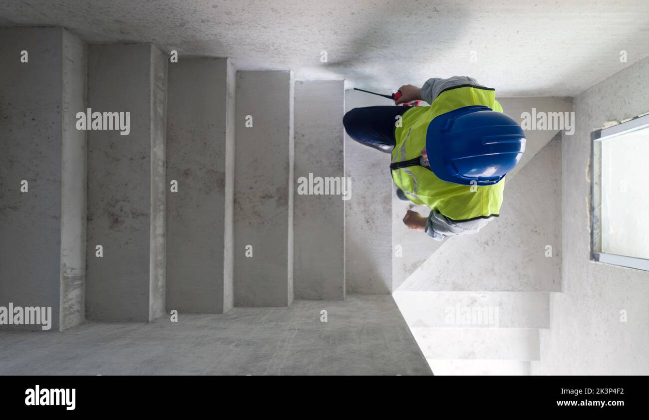 Engineer in hardhat, safety vest and Walkie-Talkie checking house ...