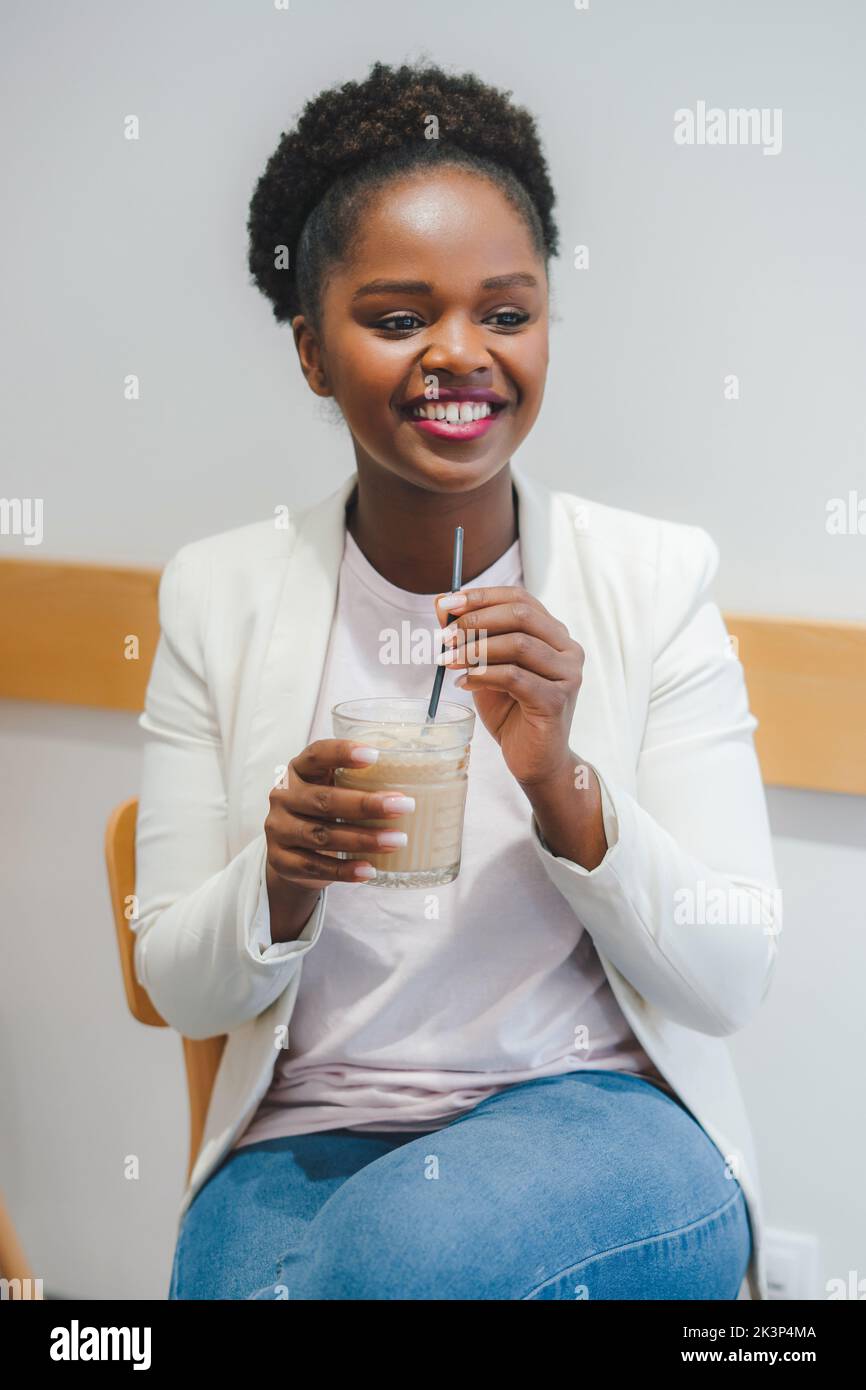Daydreaming african young businesswoman drinking a cocktail in a cafe ...