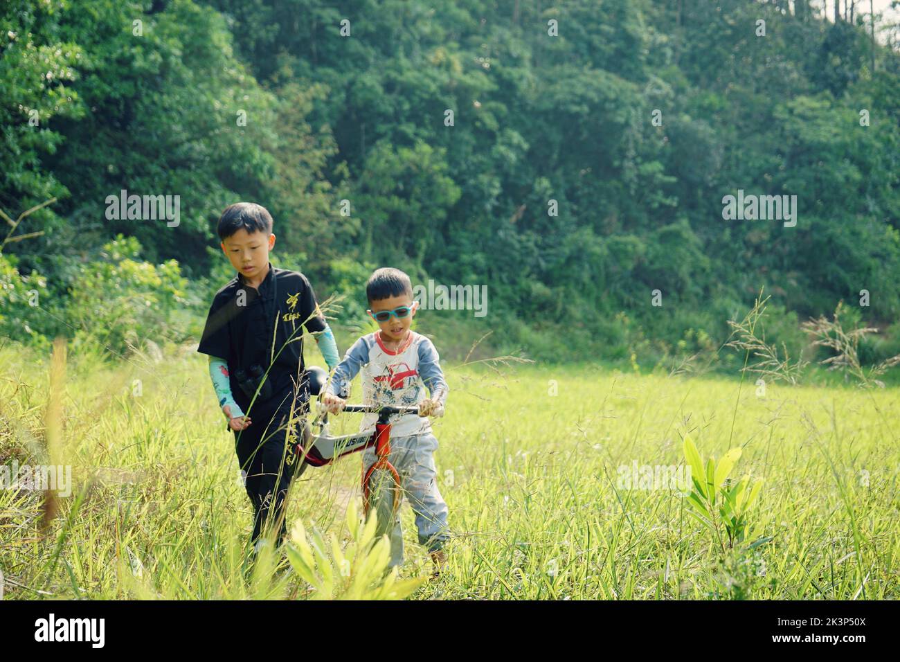 Two boys biking in a rural field in Hezhou City, Guangxi, China Stock Photo - Alamy