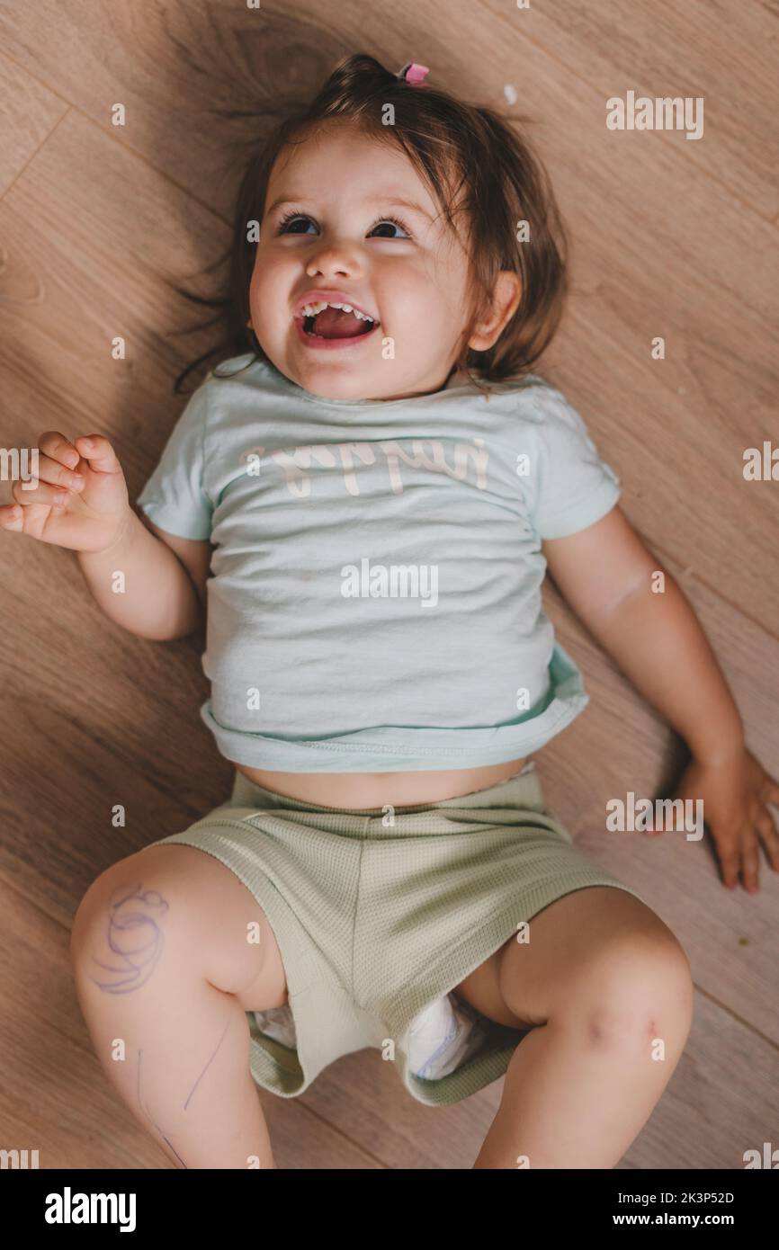 Tiny baby lying on his back on the floor and looking up, smiling ...