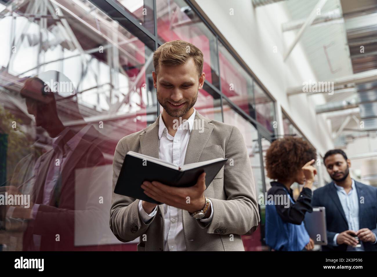 Businessman looks into notepad while standing in office against ...