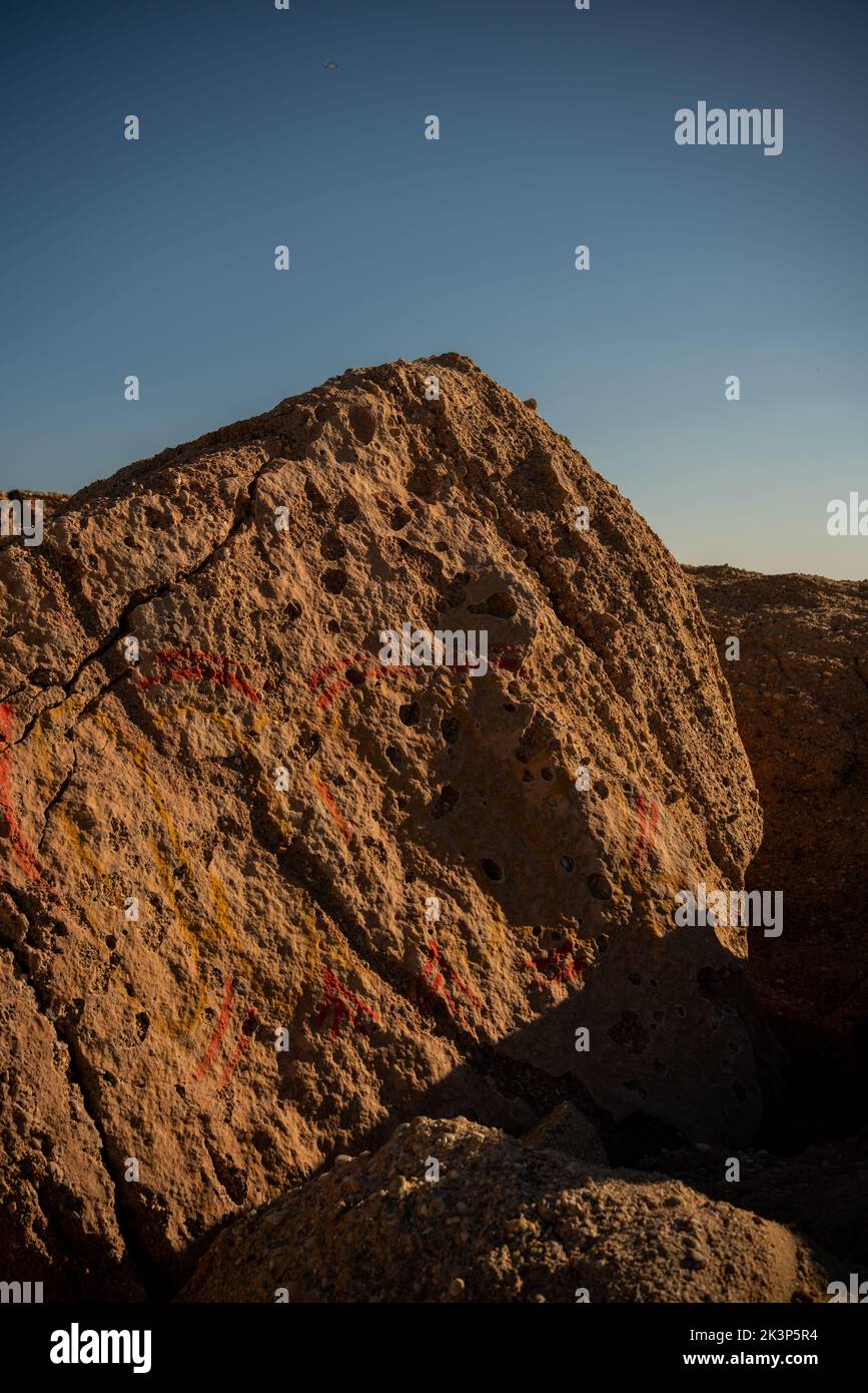 A vertical closeup of a big stone with red and yellow markings on it ...