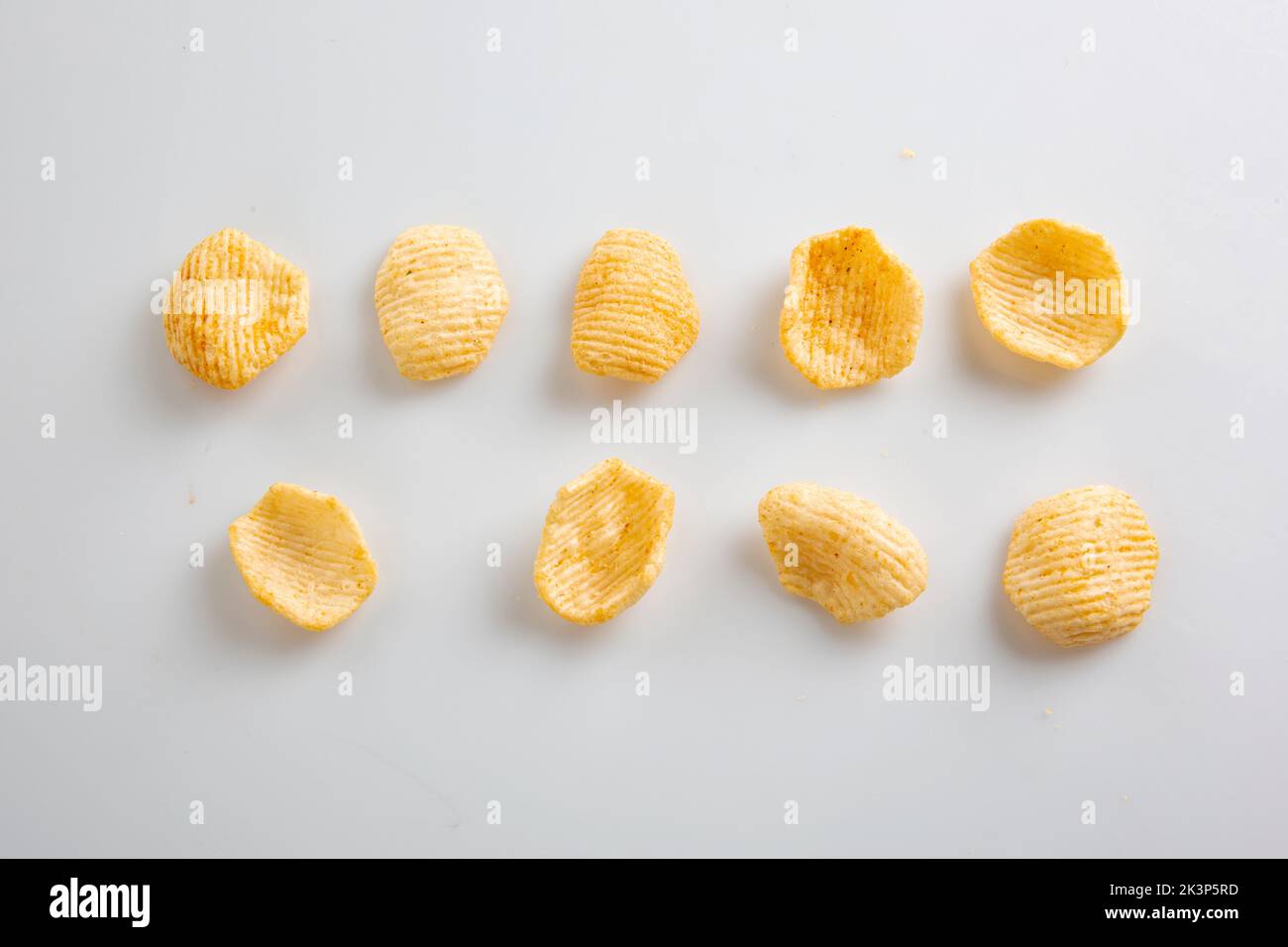 Potato chips falling into glass bowl isolated on white background with ...
