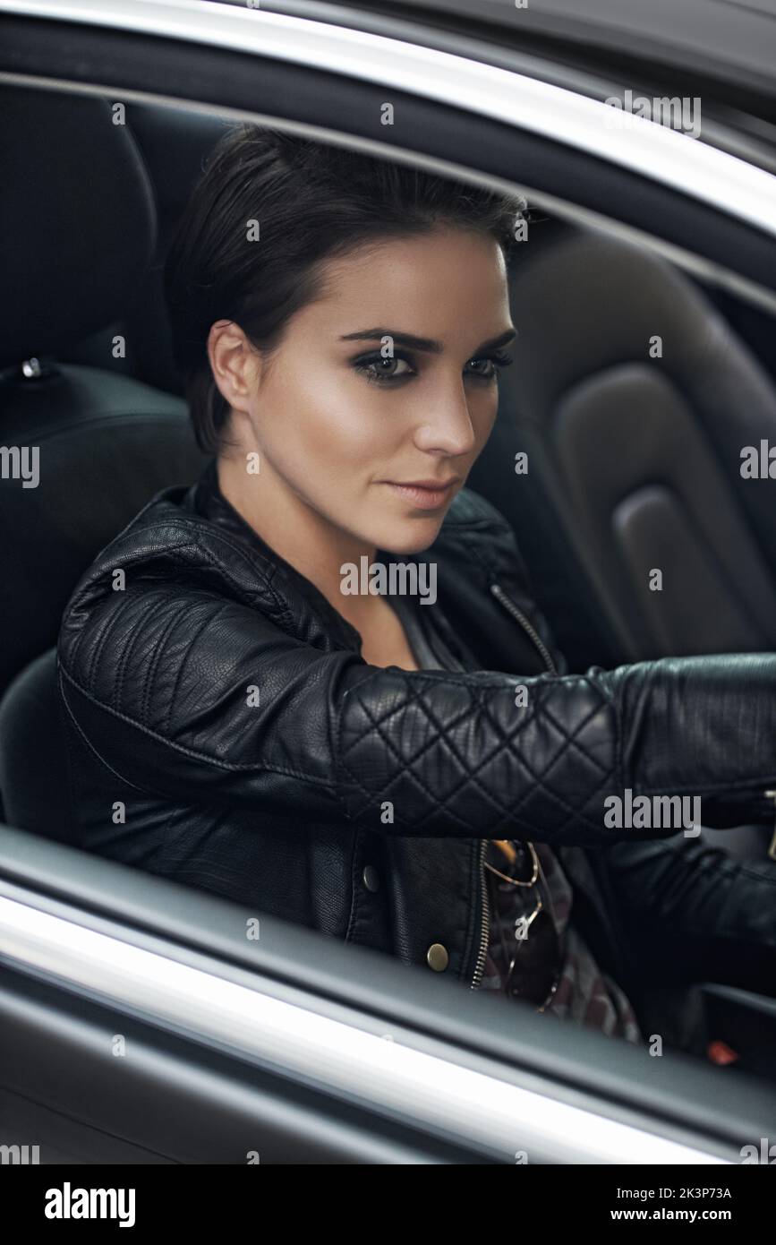 Time to get away from it all. a stylish young woman sitting in a care ...